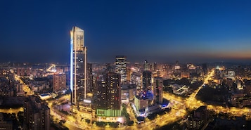 Um edifício alto com vários andares, cercado por outros edifícios e ruas.
