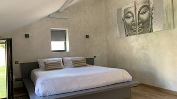 Um quarto moderno com uma cama grande, uma janela e uma obra de arte na parede.