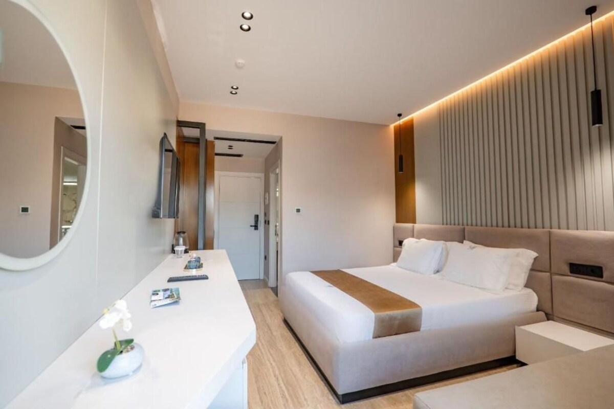 Um quarto moderno com uma cama grande, uma mesinha de cabeceira, um espelho e um aplique na parede.