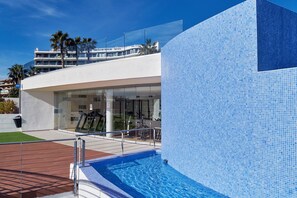 Um edifício moderno com piscina, equipamentos de ginástica e fachada de vidro.