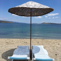 Na praia, espreguiçadeiras, guarda-sóis 
