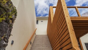 Uma escadaria de madeira leva a um terraço com vista para o céu.