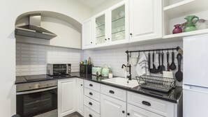 Uma cozinha moderna com armários brancos, bancada preta, forno de aço inoxidável e micro-ondas.