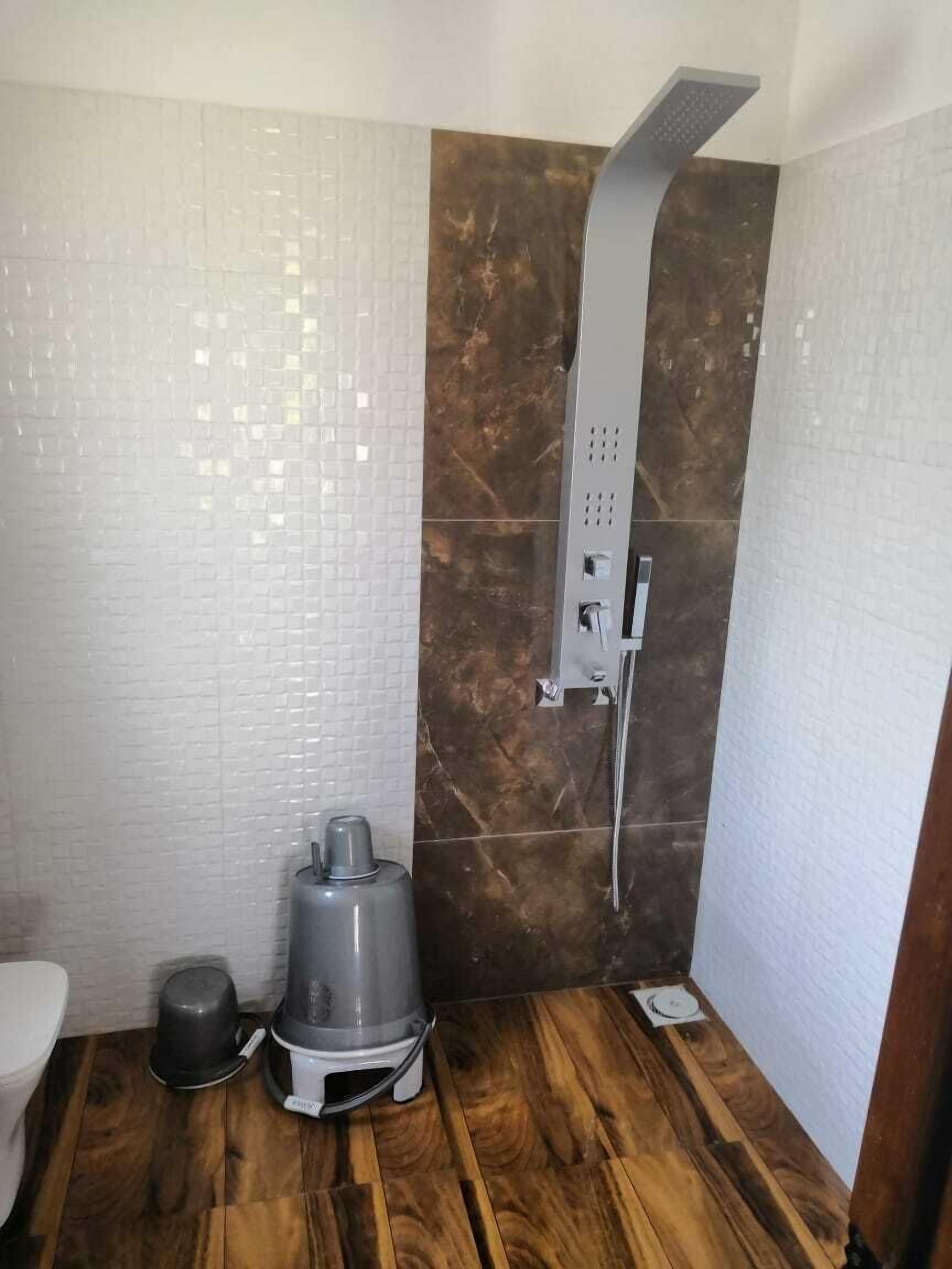 Casa de banho com chuveiro, sanita e lavatório moderno e compacto.