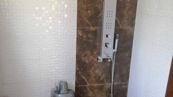 Casa de banho com chuveiro, sanita e lavatório moderno e compacto.