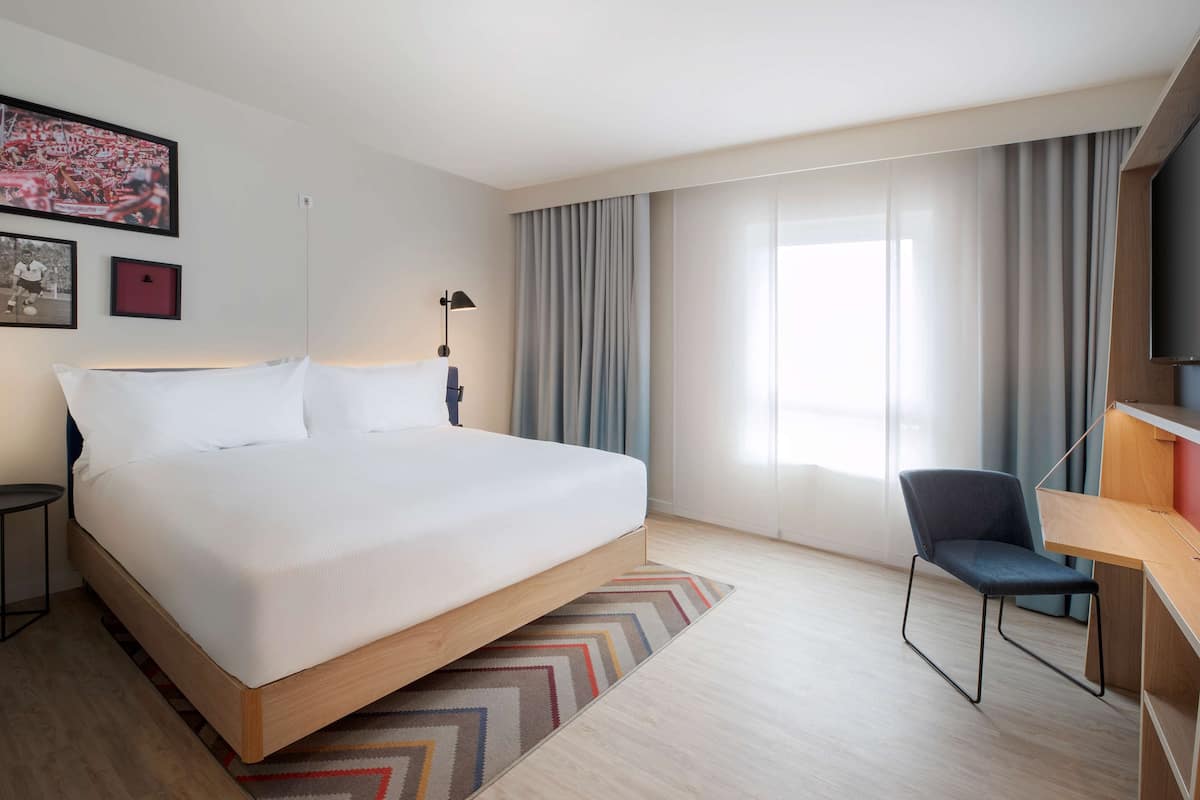 Quarto de hotel moderno com uma cama grande, uma mesa e uma cadeira.