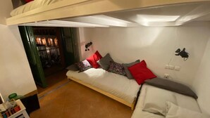 Quarto compacto com cama, sofá e uma pequena mesa.