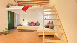 Quarto estilo loft com cama beliche, escada e sofá-cama.