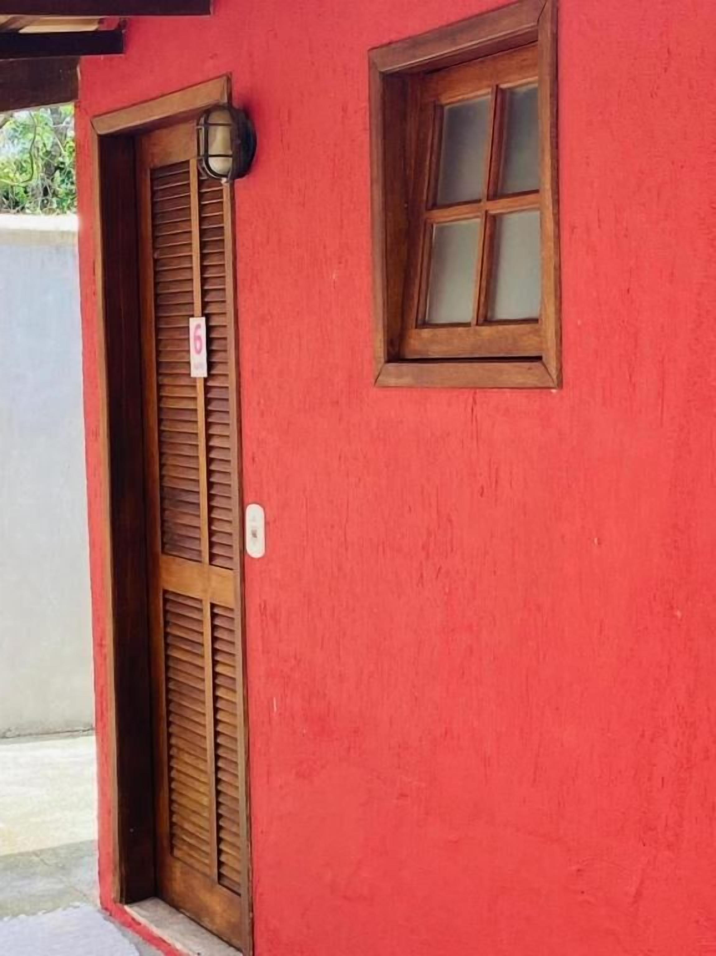 Um edifício vermelho com porta de madeira e uma pequena janela.