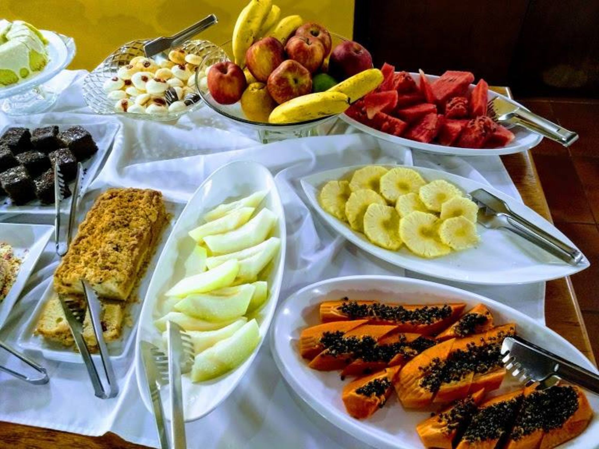 Um buffet com diversas frutas, legumes e sobremesas.
