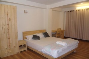 Quarto com cama de madeira, mesa de cabeceira, guarda-roupa de madeira e escrivaninha com cadeira.