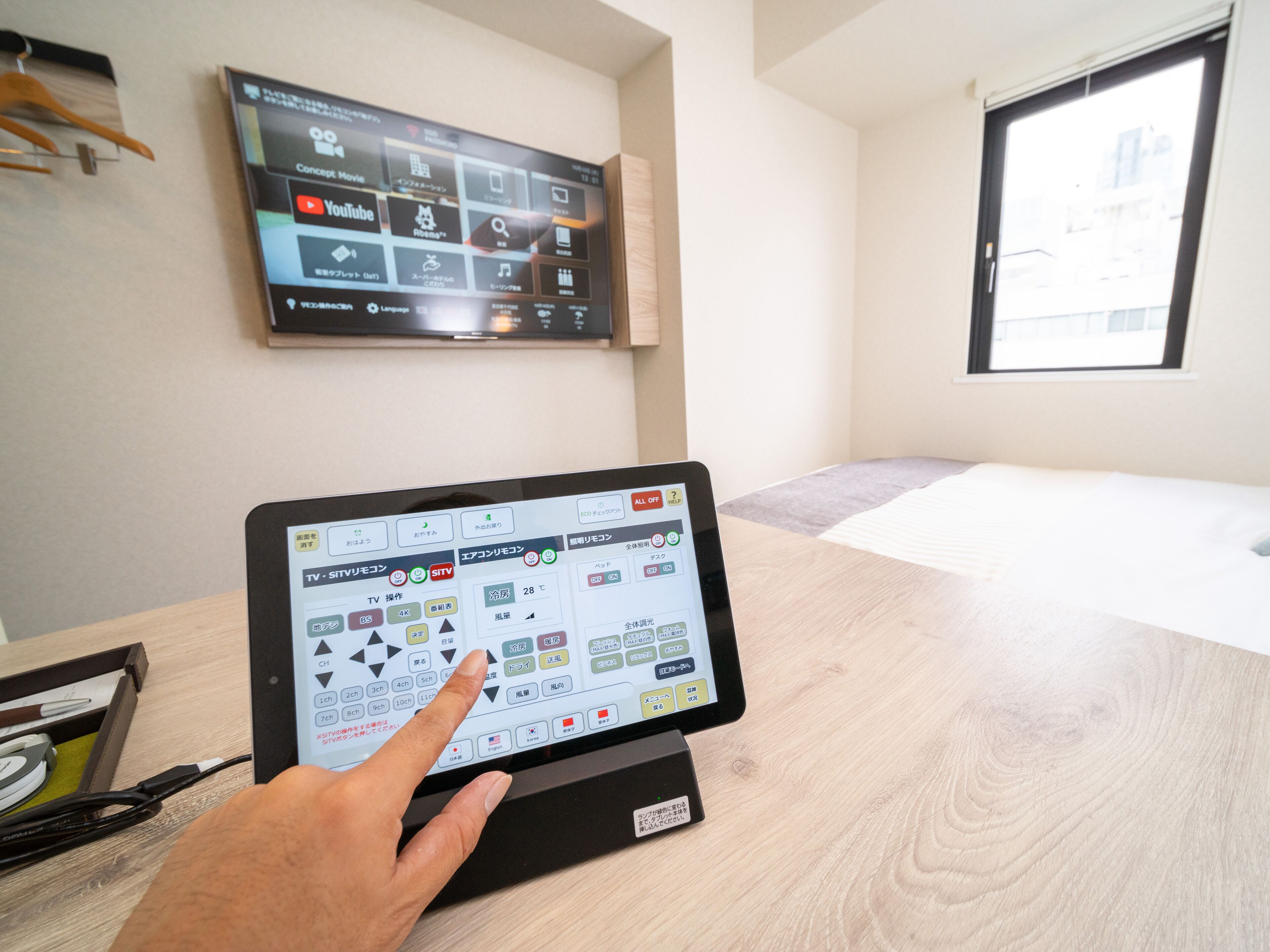 Um tablet apoiado em uma mesa de madeira exibindo um guia de programação de televisão em japonês.