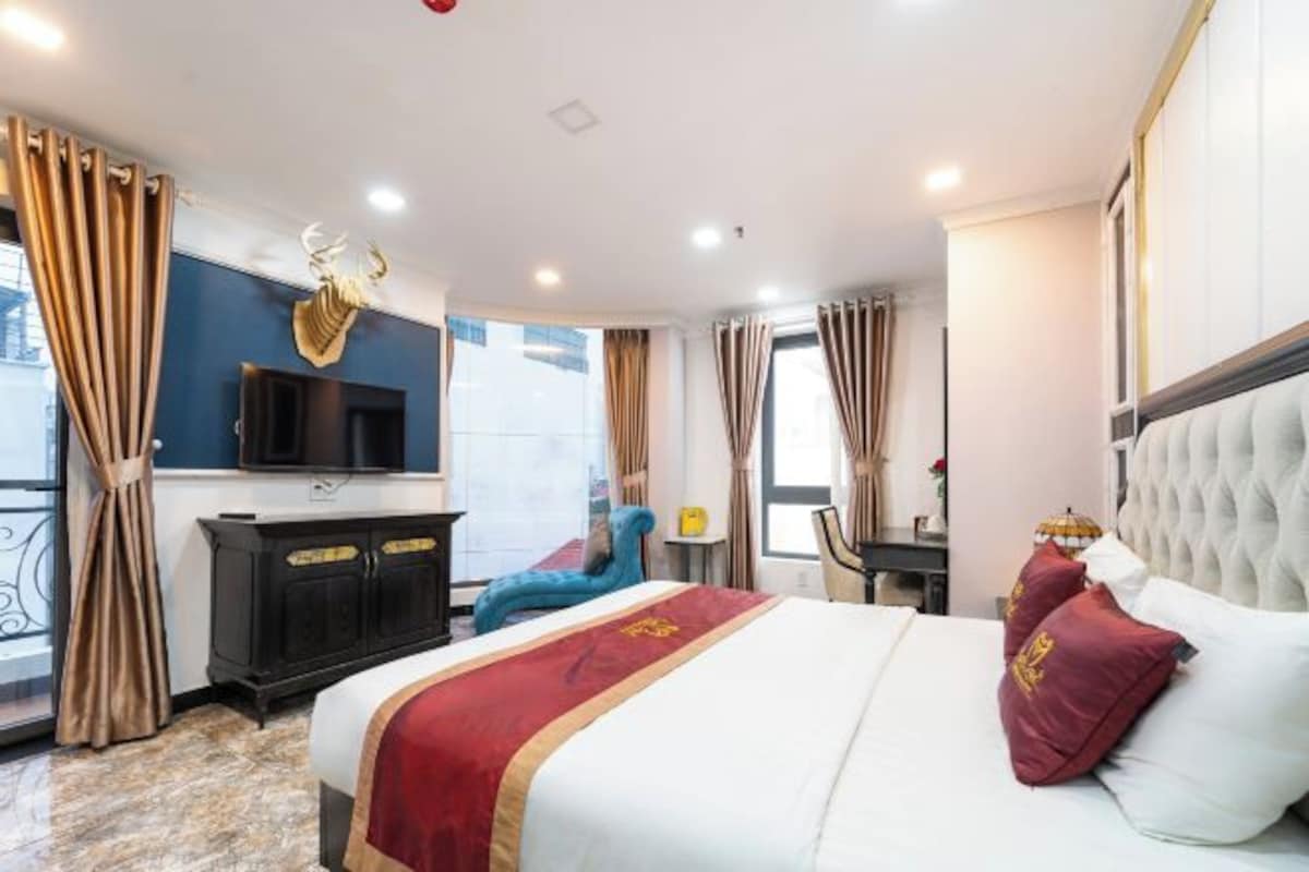 Quarto de hotel com cama, televisão, escrivaninha e cadeira.