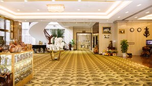 Um hall de hotel com carpete estampado, um balcão de recepção e uma escadaria.