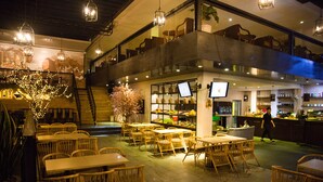Um restaurante com área externa, bar e escada que leva a um andar superior.