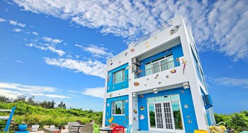 Um edifício de dois andares com fachada azul e branca, decorado com adesivos de peixes e criaturas marinhas.