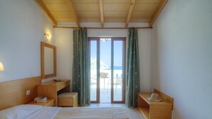 Quarto de hotel com cama, mesa de cabeceira, espelho, escrivaninha e vista para o exterior.
