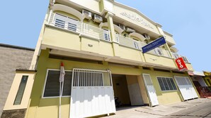 Um edifício de vários andares com varandas, uma placa com 'BAVLIUN PERMATA' e um letreiro vermelho 'OYO'.