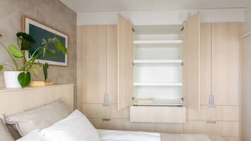 Quarto com cama, guarda-roupa, prateleira com planta e quadro na parede.