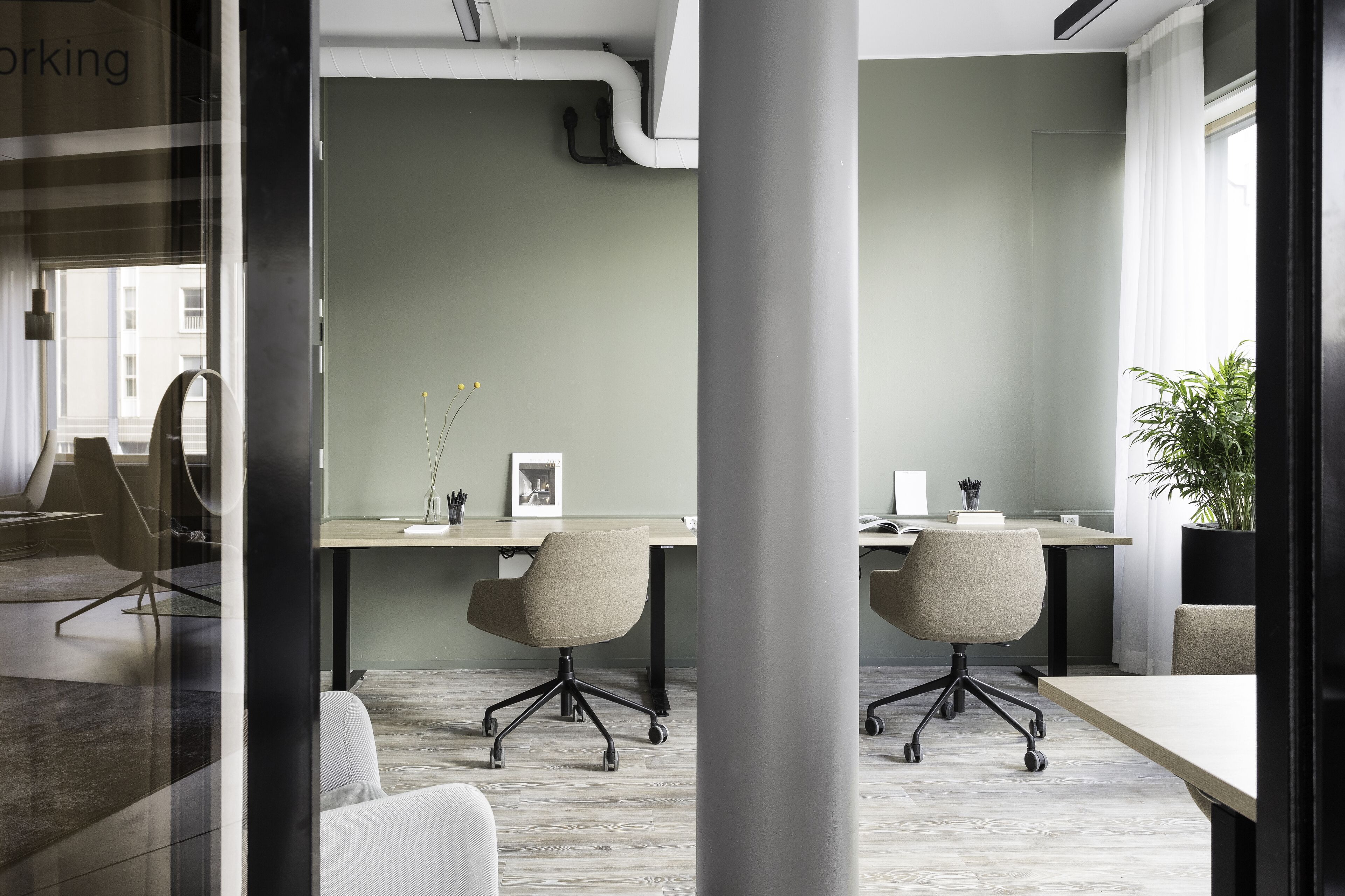 Um espaço de escritório moderno com duas mesas, cadeiras e um vaso de planta.
