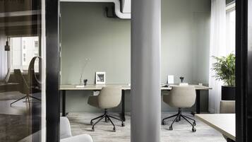 Um espaço de escritório moderno com duas mesas, cadeiras e um vaso de planta.