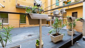 Jardim no terraço com vasos de plantas e guarda-corpo de metal.