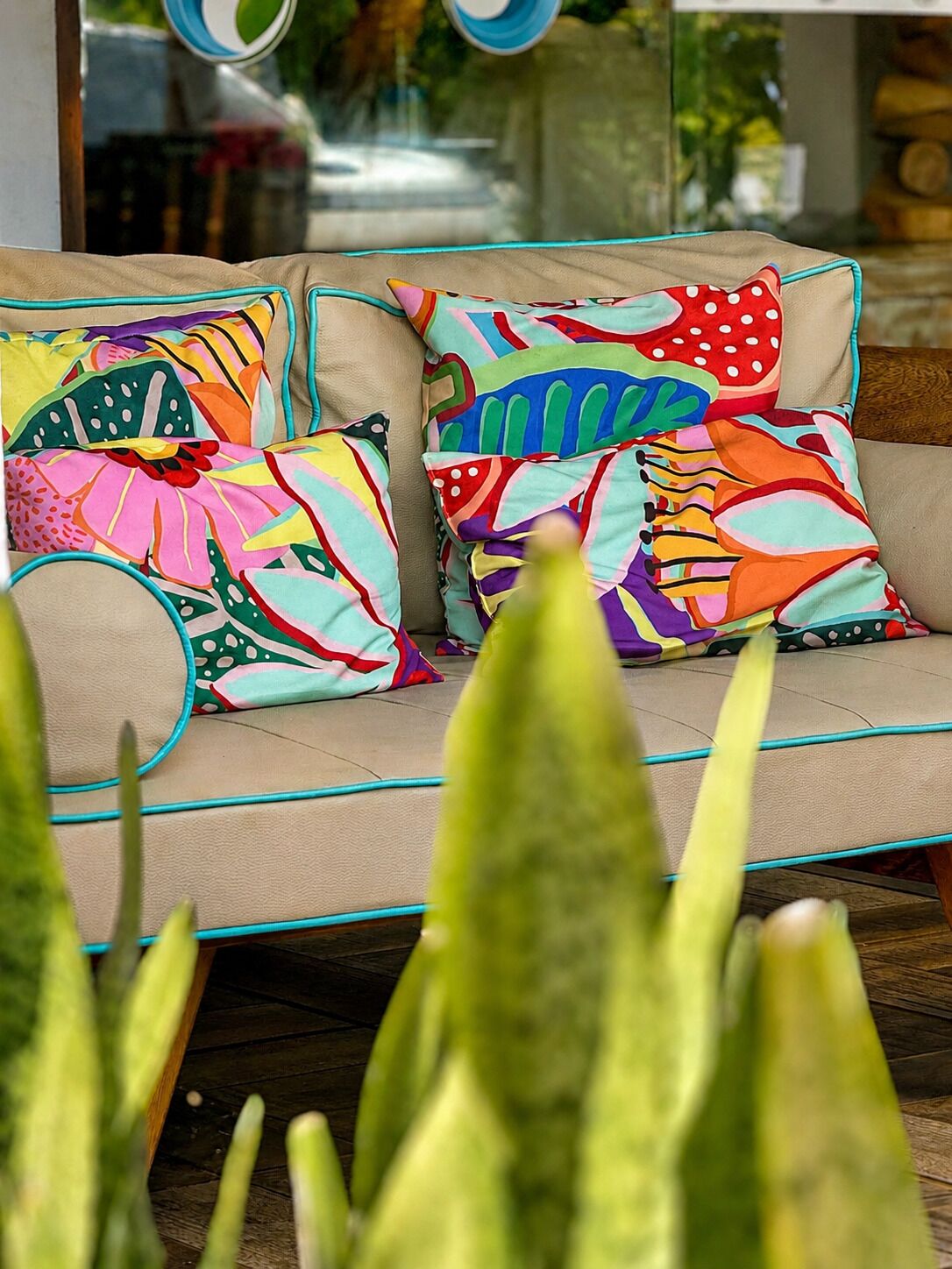 Sofá com almofadas coloridas e vista para um jardim.