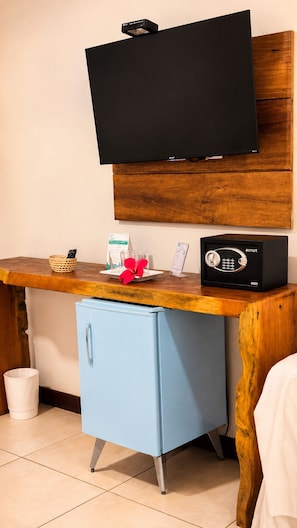 Uma cozinha compacta com uma televisão fixada acima de um balcão de madeira, um frigorífico pequeno azul e um rádio sobre o balcão.