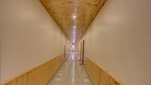 Um corredor comprido e estreito, com paredes de madeira e piso lustroso, que leva a uma porta no final.