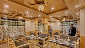 Um restaurante com mobiliário de madeira e um lustre moderno.