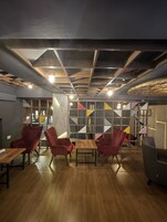Um interior moderno com painéis de parede geométricos, piso de madeira e cadeiras estofadas em vermelho.