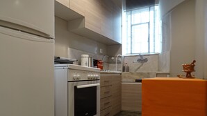 Uma cozinha compacta com forno embutido, pia e janela que oferece luz natural.