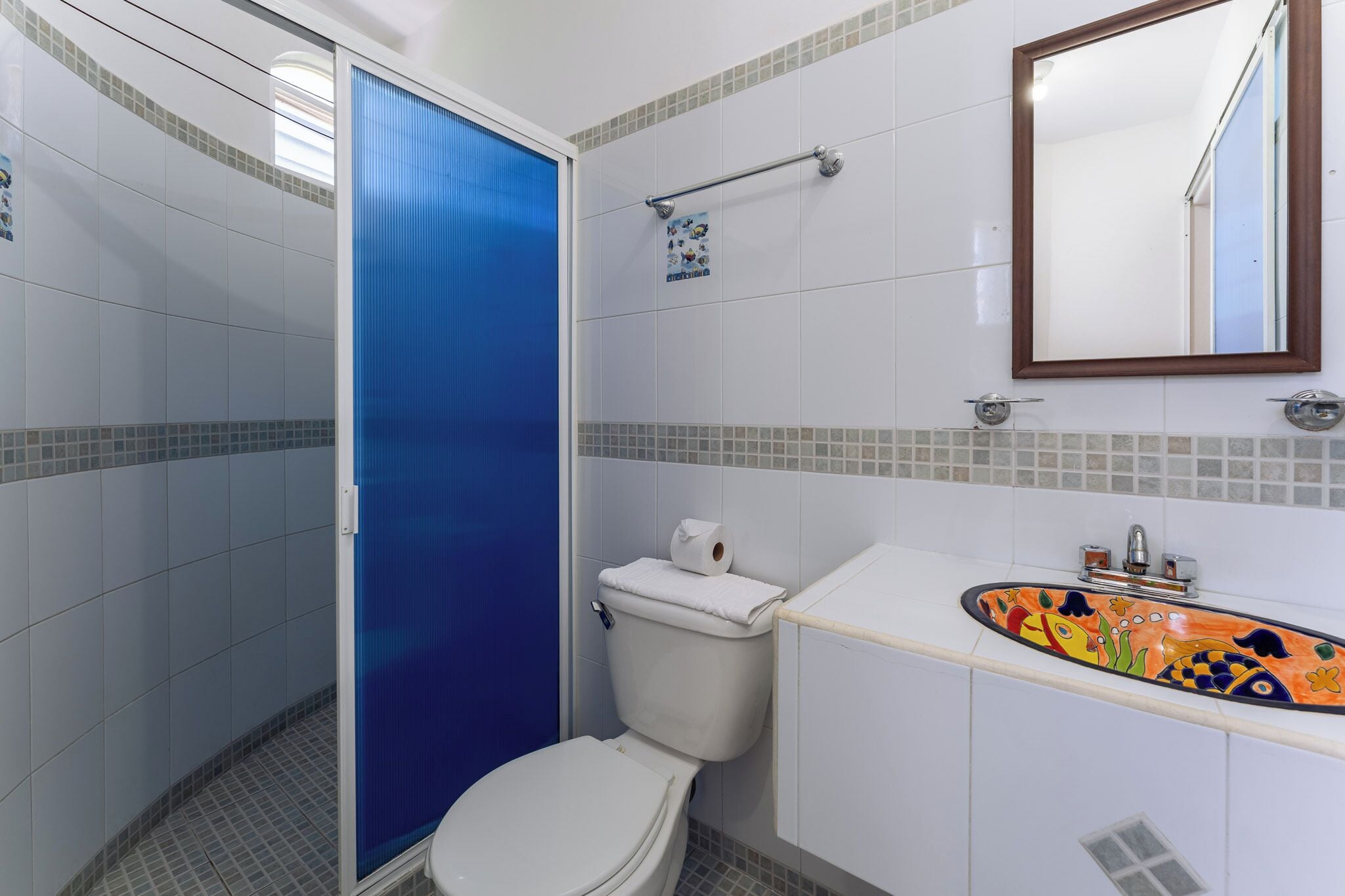 Uma casa de banho com sanita, lavatório e uma área de duche.
