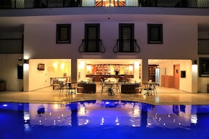 Área da piscina com bar e assentos.