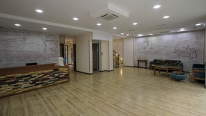 Um hall amplo com balcão de atendimento em madeira, escada e sofá.
