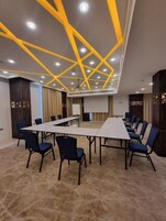 Uma sala de conferências com uma mesa comprida, cadeiras azuis e um design moderno no teto.