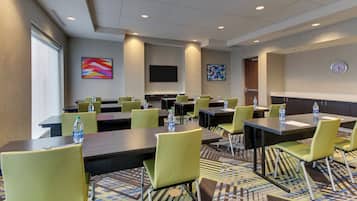 Uma sala de conferências com mesas, cadeiras e um relógio na parede.