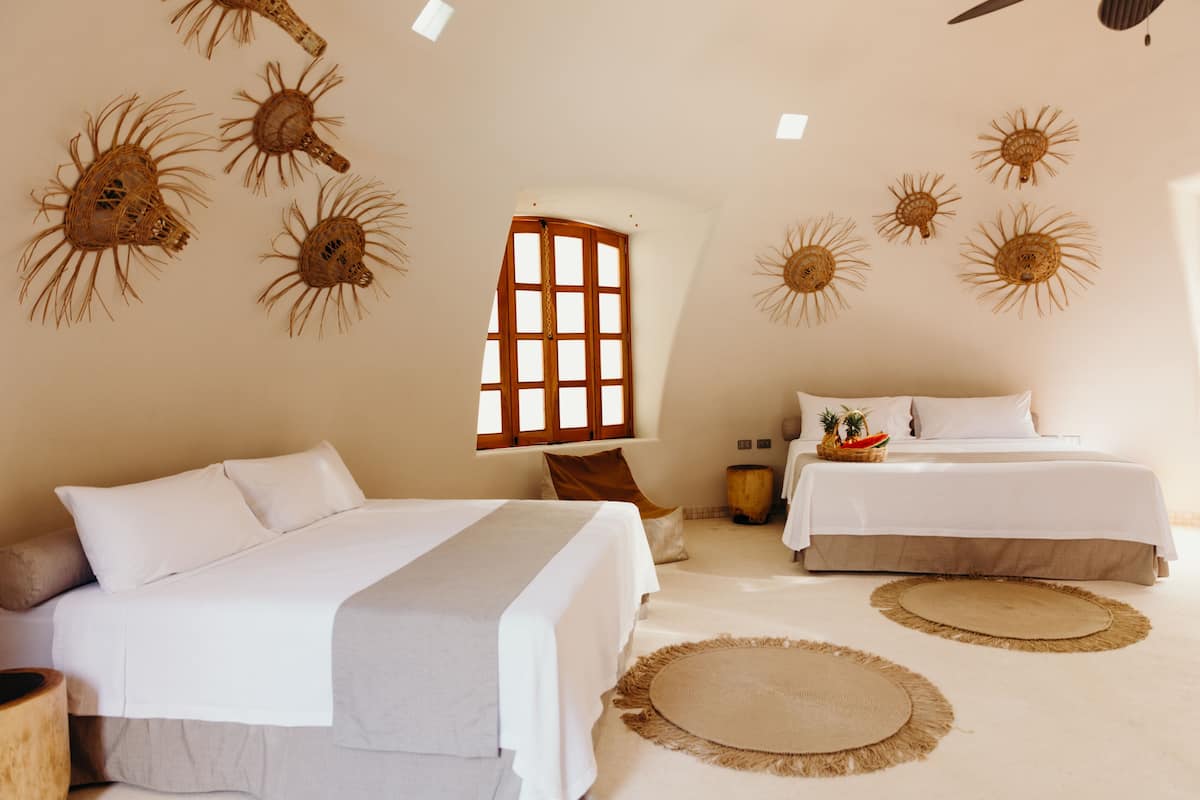 Quarto com duas camas, uma janela e detalhes na parede.