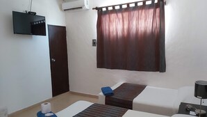 Quarto de hotel com duas camas, uma televisão, ar condicionado e cortina.