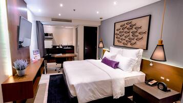 Quarto de hotel moderno com uma cama grande, mesas de cabeceira, uma escrivaninha e uma cadeira.