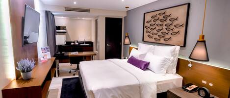 Quarto de hotel moderno com uma cama grande, mesas de cabeceira, uma escrivaninha e uma cadeira.