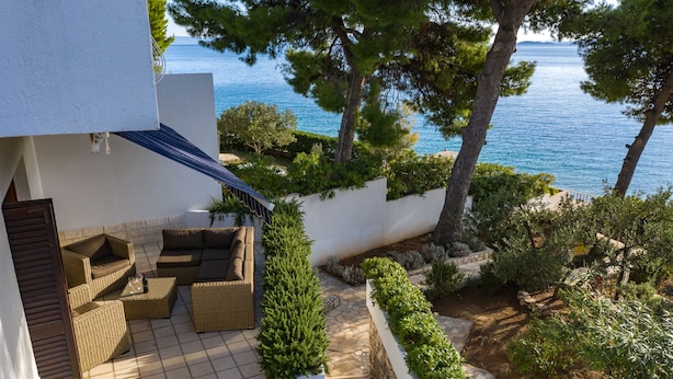 Um terraço com mobiliário de exterior, vista para o mar e um jardim ajardinado.