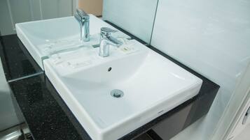 Um banheiro com duas pias, cada uma com uma torneira moderna, e um espelho sobre elas.