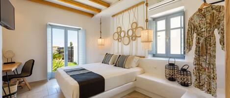 Quarto com cama grande, uma escrivaninha e uma cadeira, janela com cortinas e luminária pendente.