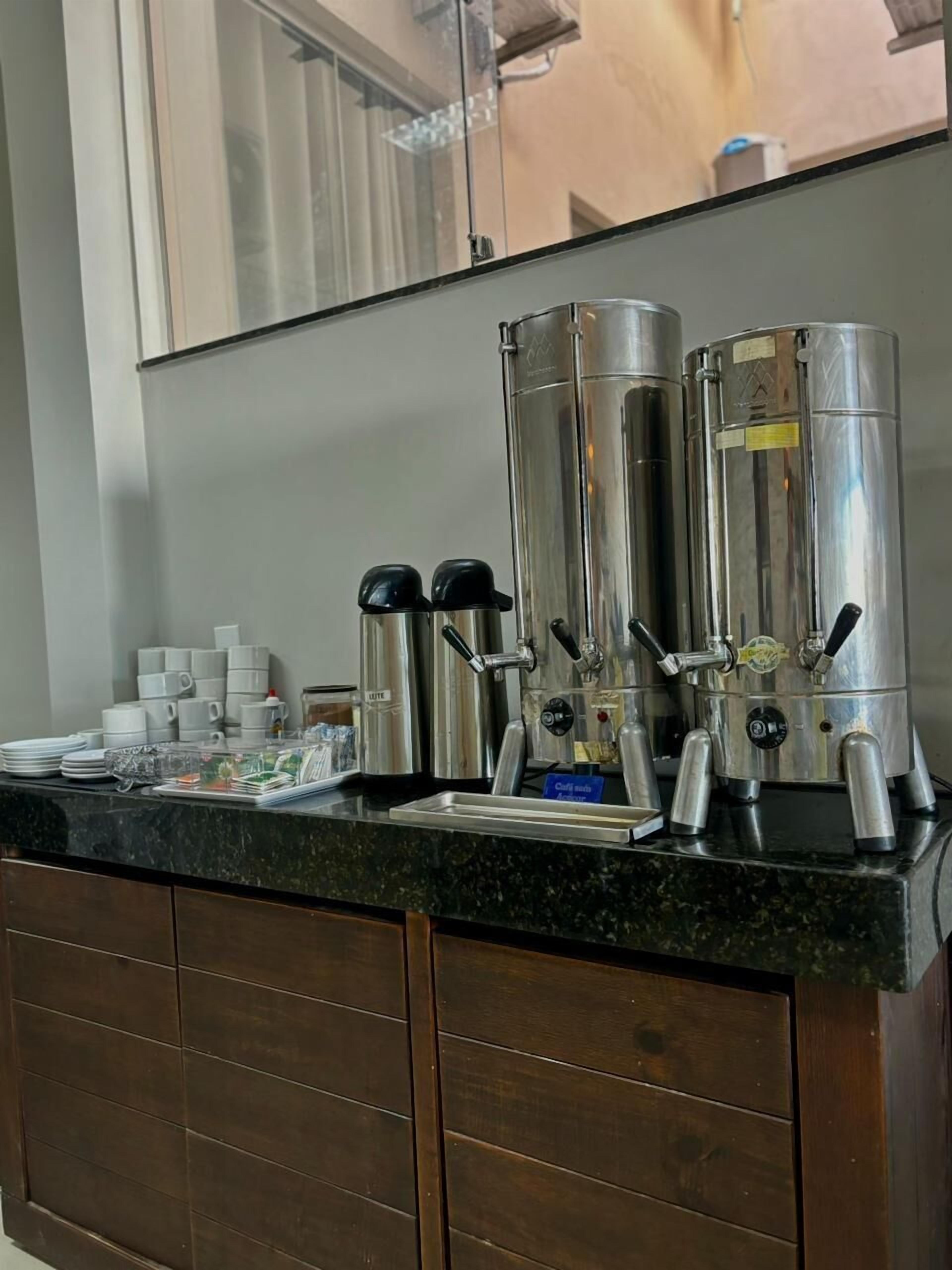Uma cozinha com eletrodomésticos em aço inoxidável, incluindo uma máquina de café e uma chaleira, em bancada de granito.