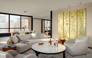 Uma sala de estar moderna com sofá, poltronas, mesa de centro e painel decorativo na parede.
