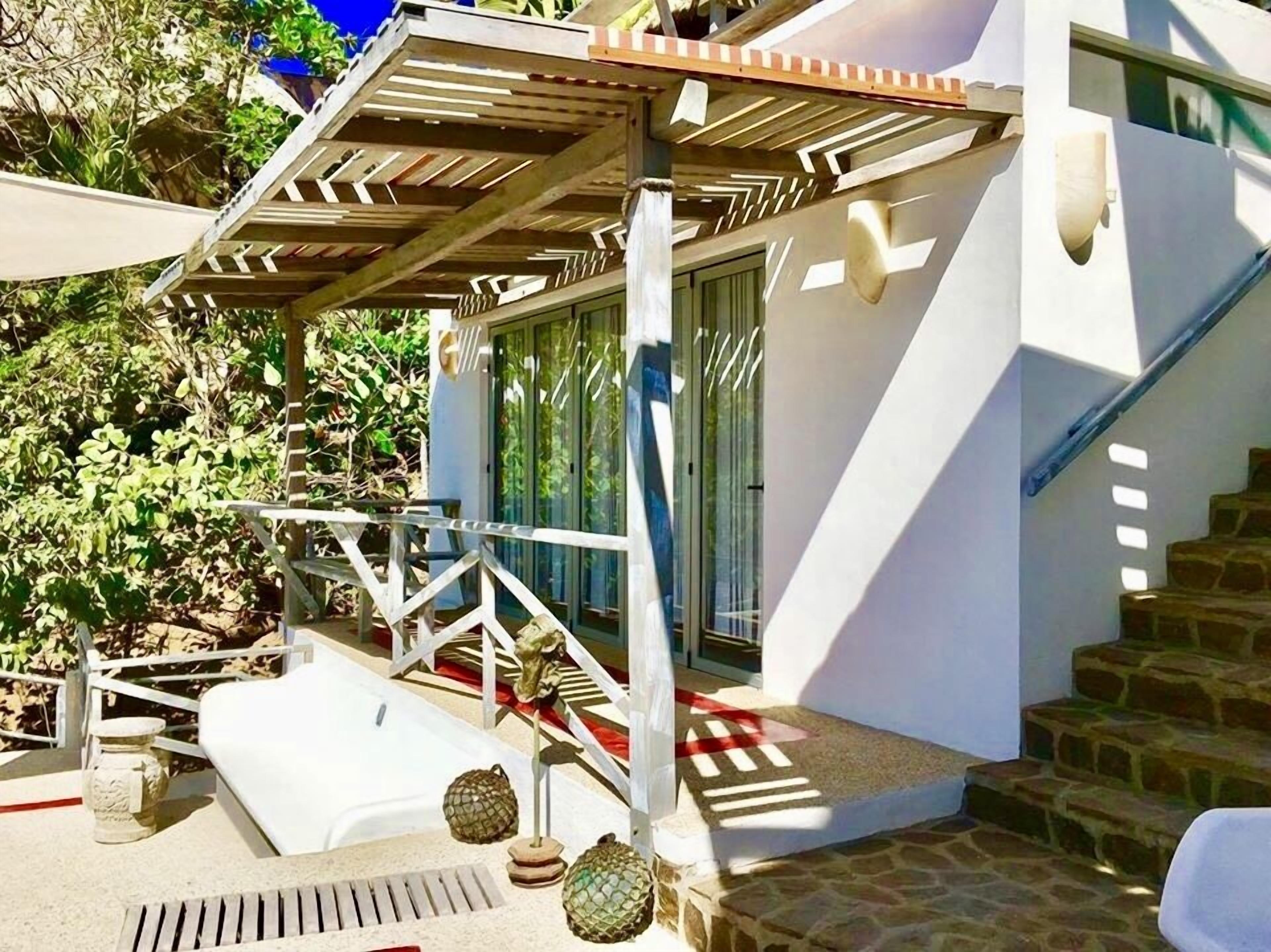 Uma casa moderna com área externa coberta, escadaria e jardim.