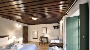 Quarto com duas camas, uma escrivaninha, uma cadeira, uma televisão e um guarda-roupa.