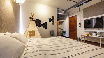 Quarto com cama, tenda, televisão e escrivaninha.