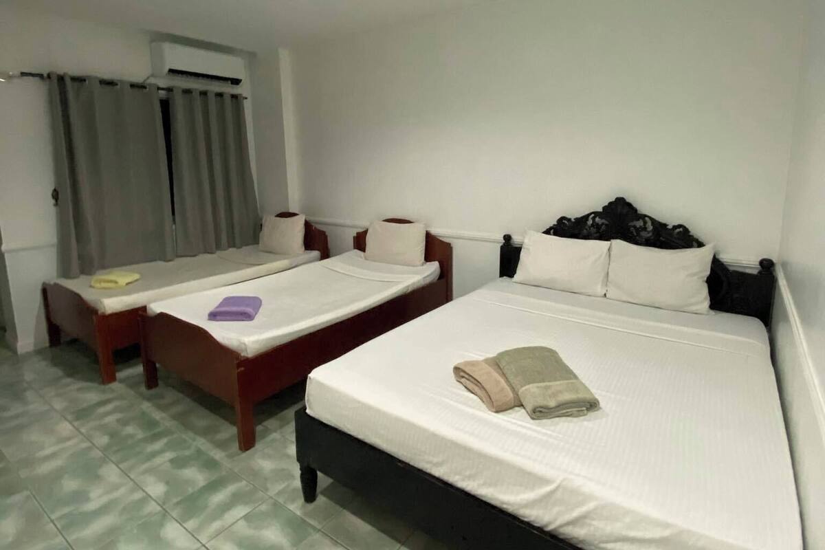Quarto de hotel com duas camas de solteiro, um sofá e uma mesa pequena.